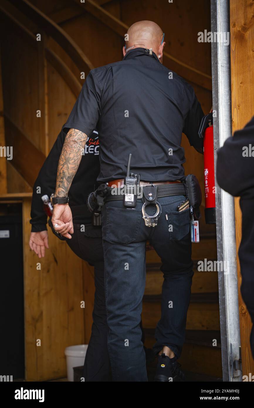 Security guard in black uniform walks up a wooden staircase, Canstatter ...