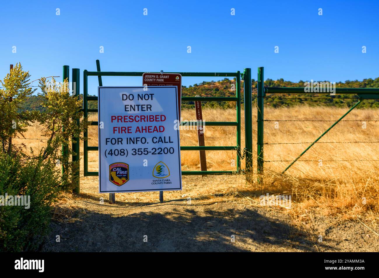 A closed gate with a safety sign informing about a prescribed fire ...