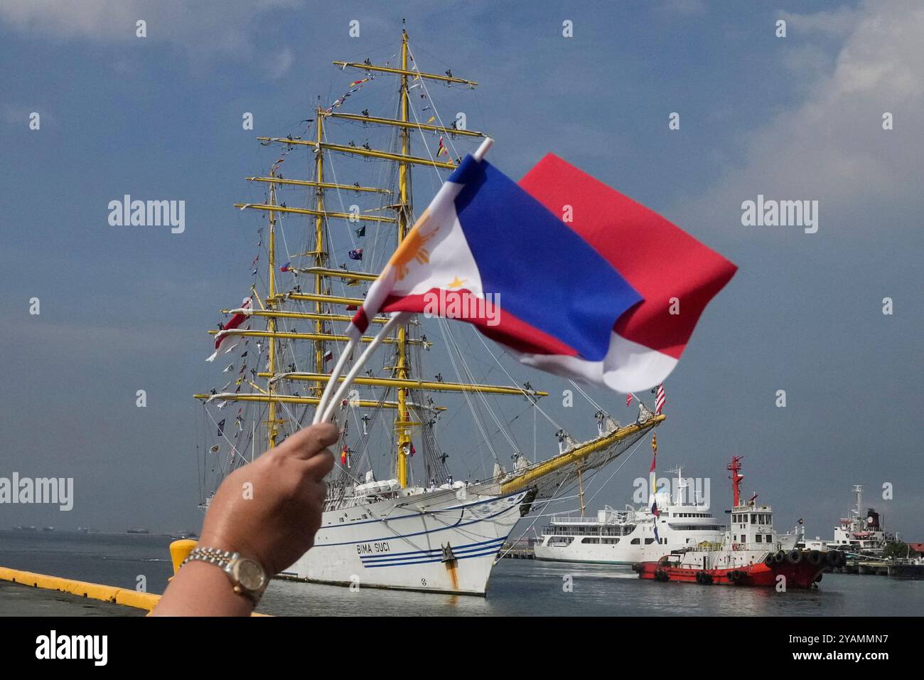 A woman waves the Philippine and Indonesian flags as Indonesian Navy ...