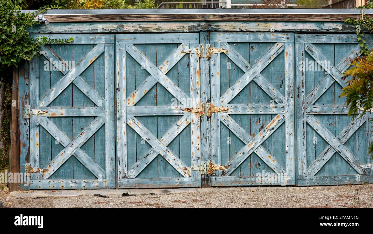 A rustic, weathered blue wooden gate with crisscrossed wooden beams and ...