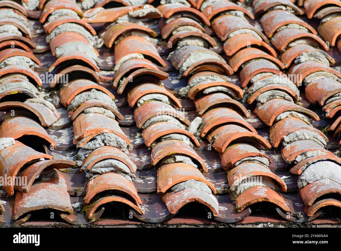 Aged terracotta tile roof with uneven and cracked tiles, showing signs ...