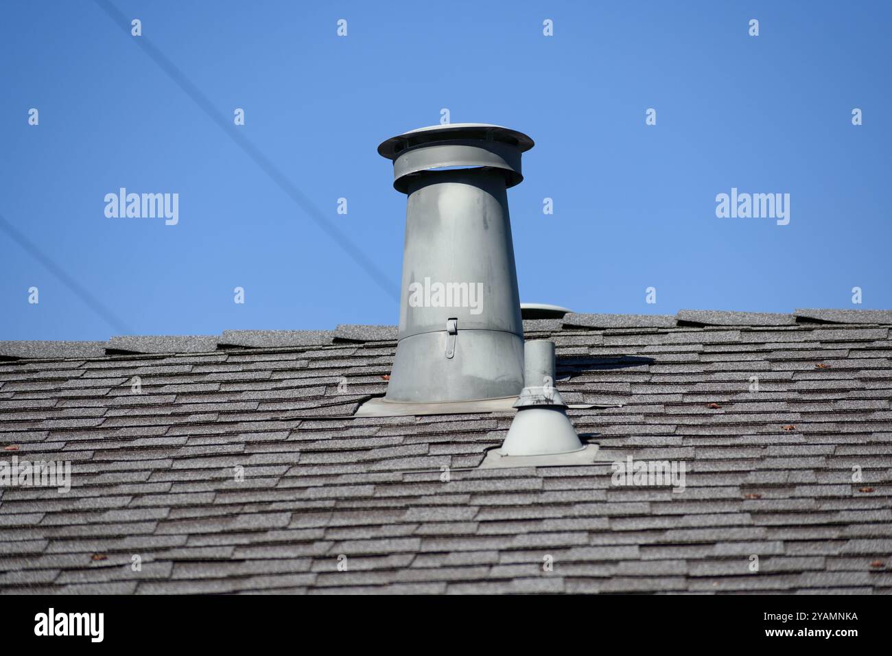 Metallic chimney and a smaller roof vent protrude from a gray shingle ...