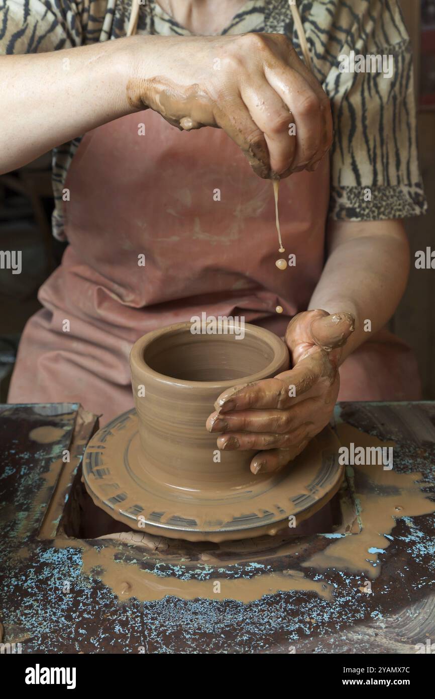 The hands of a potter, creating an earthen jar on the circle, close-ups ...