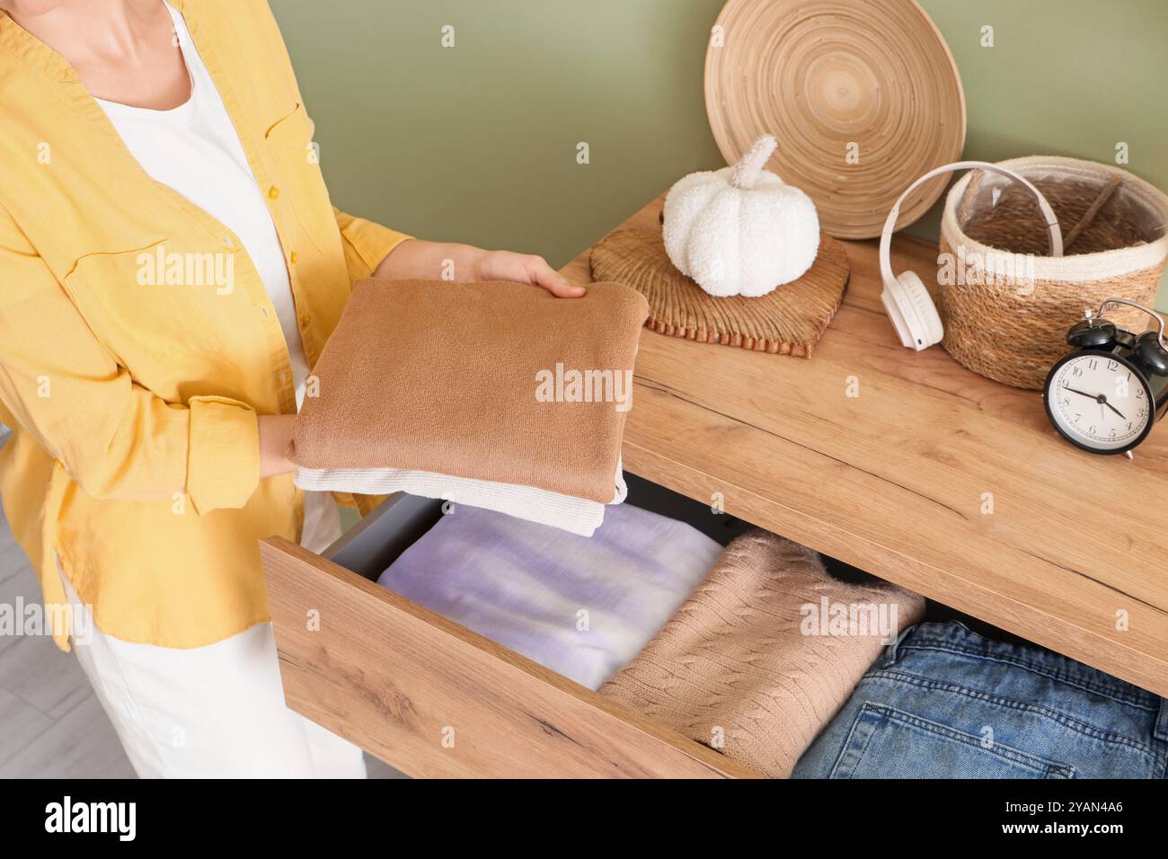 Young woman putting stack of clean clothes into dresser at home Stock ...
