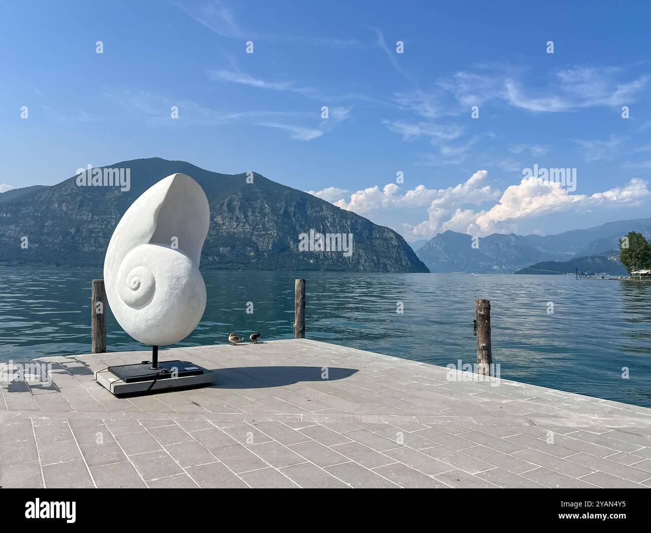 Abstract White Snail Shell Sculpture on a Stone Dock by a Calm Lake ...