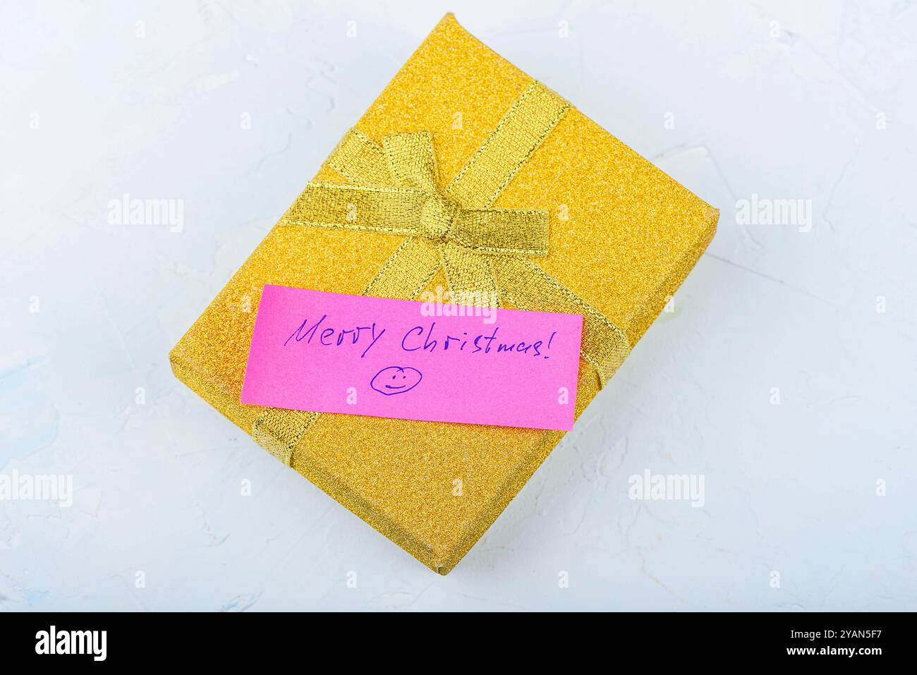 A beautifully wrapped gold gift box with a handwritten note on a light background, conveying ...