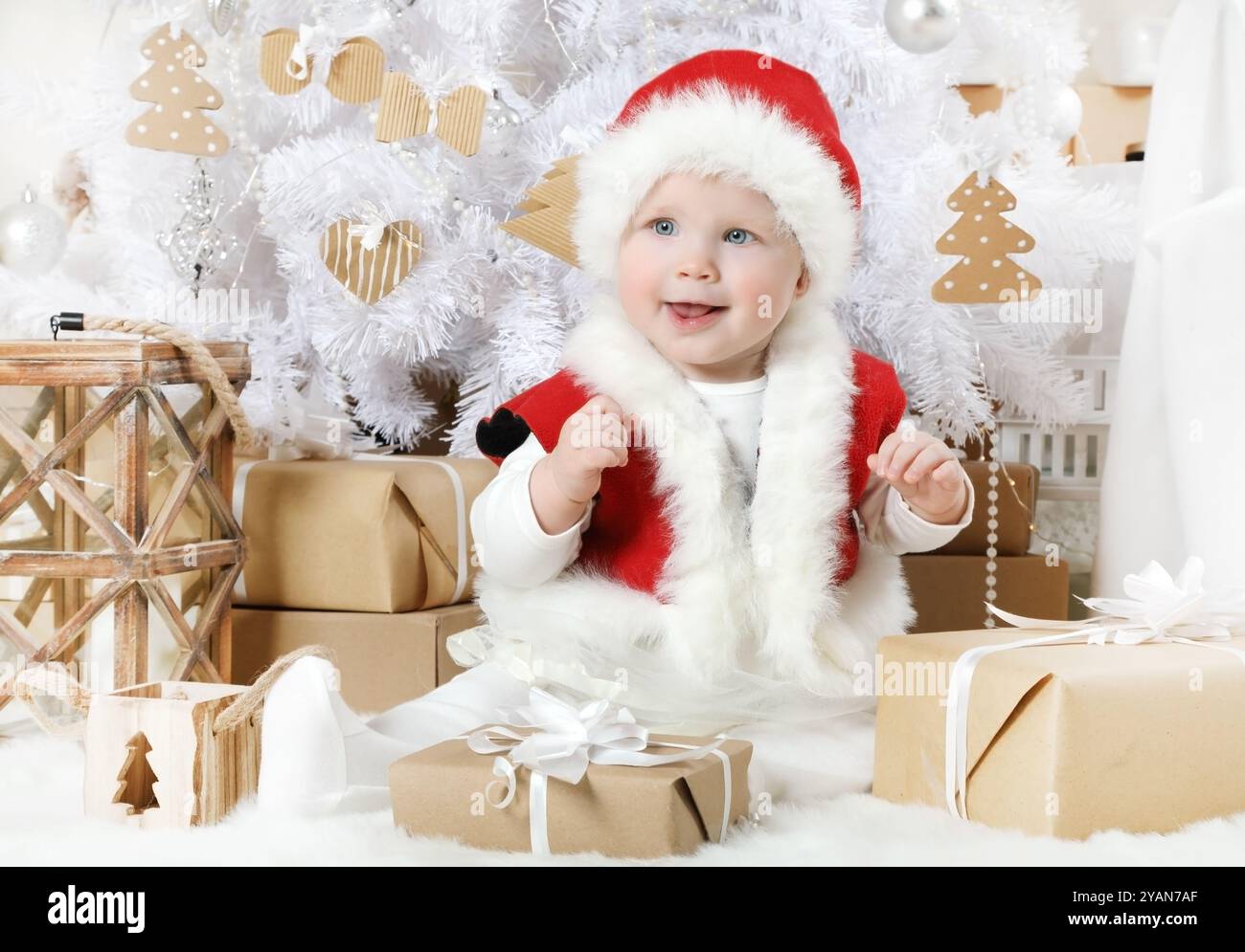 Pretty little girl (eight months of age) dressed as Santa sitting under ...