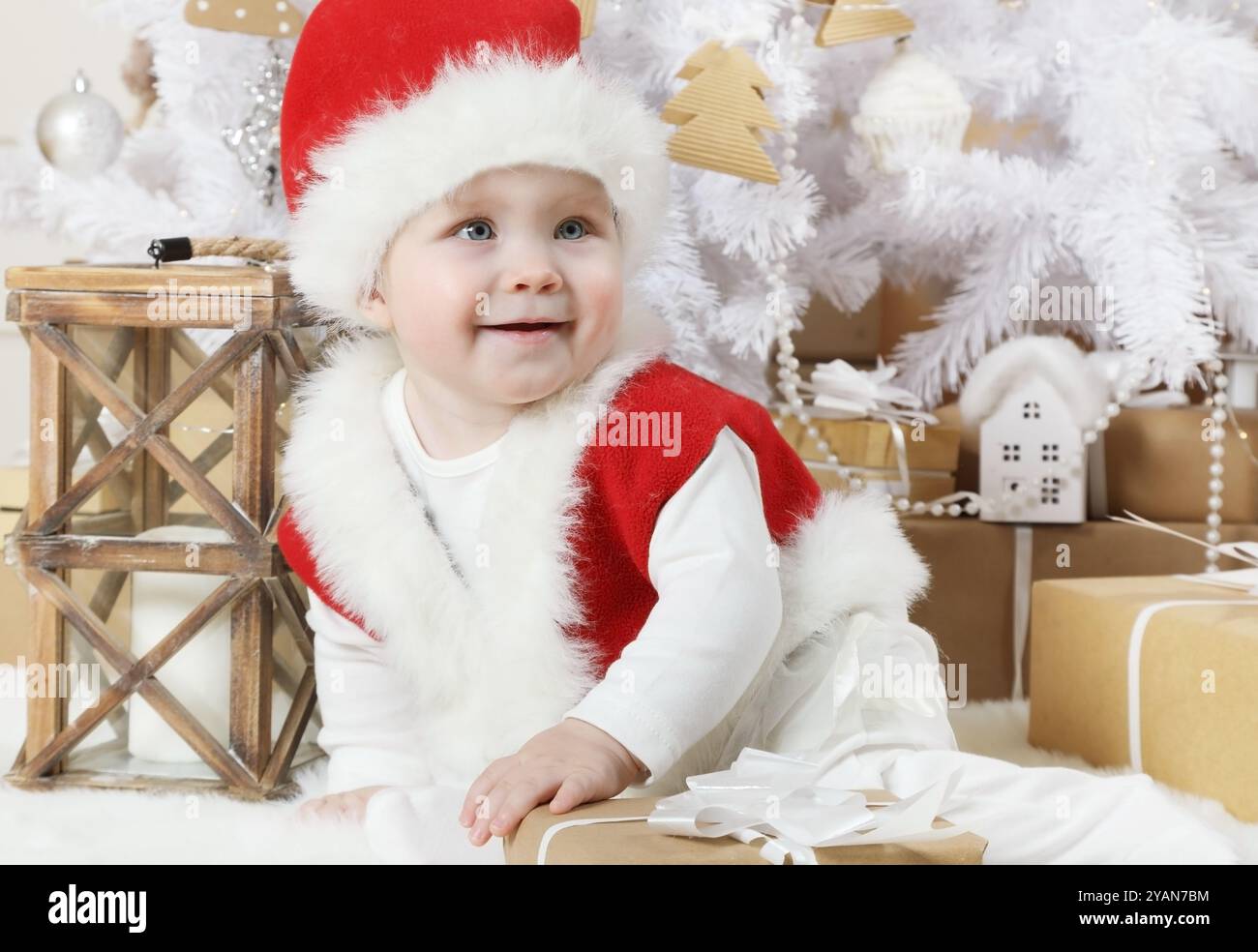 Sweet little girl (eight months of age) dressed as Santa sitting under ...