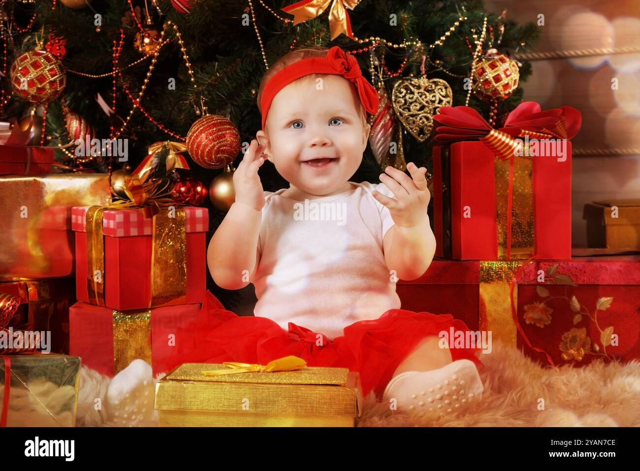 Cute little girl (eight months of age) in red sitting under the ...