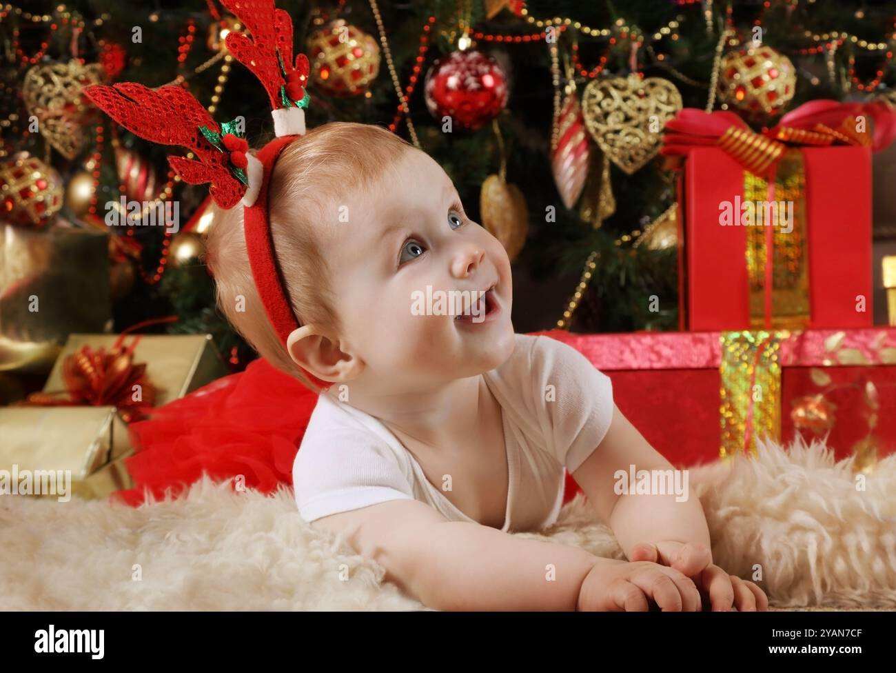 Cute little girl (eight months of age) in a hat with antlers sitting ...