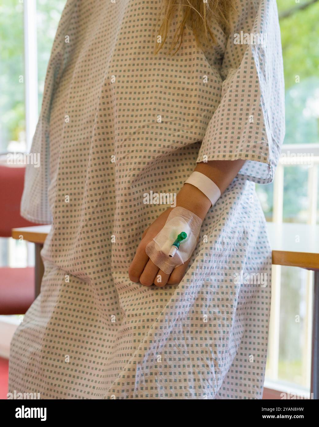 Young woman walking slowly through hospital after surgery with an ...