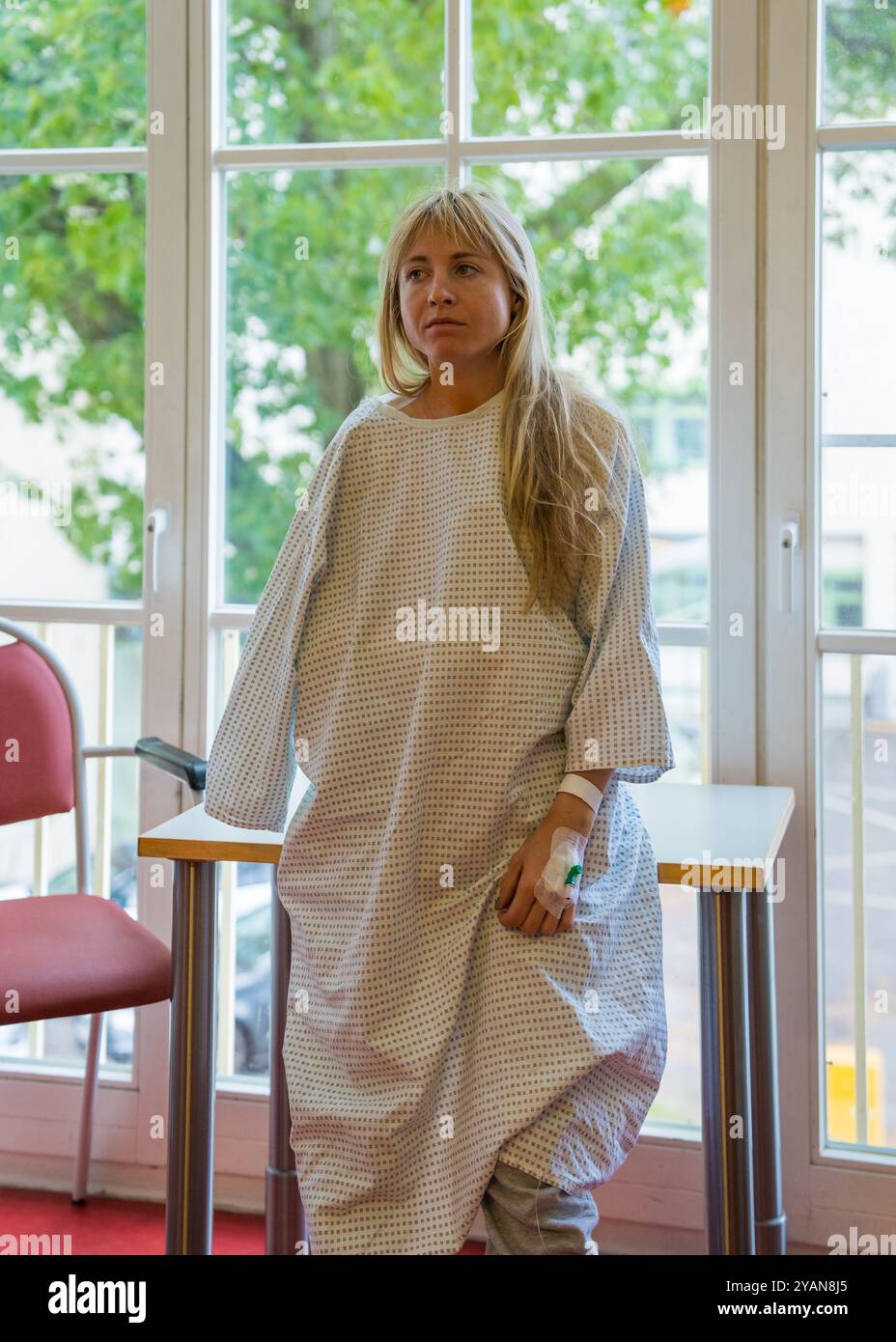 Young woman walking slowly through hospital after surgery with an ...