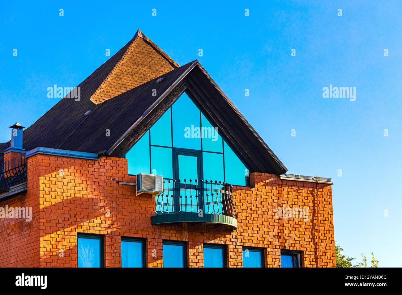 view of red brick house with glazed balcony. house with a high gable ...