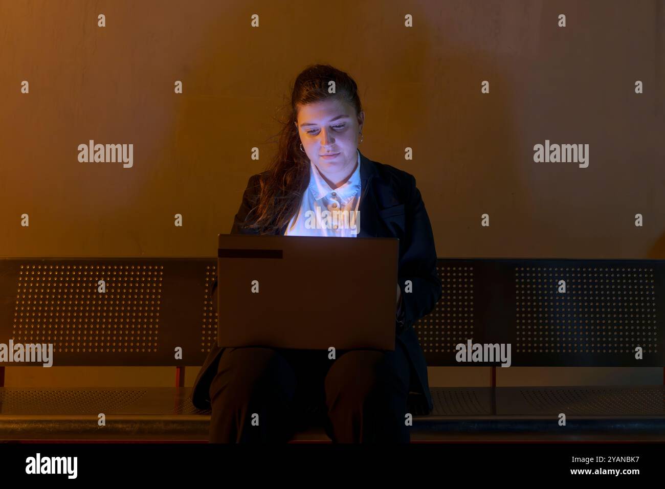 oung Woman in Business Attire Working on Laptop While Waiting for Train ...