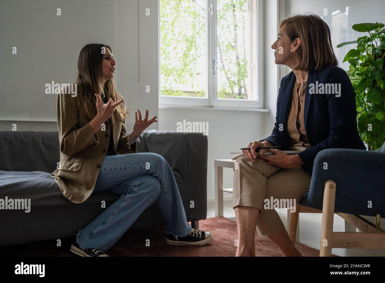 Young woman expressing emotions during therapy session with attentive ...