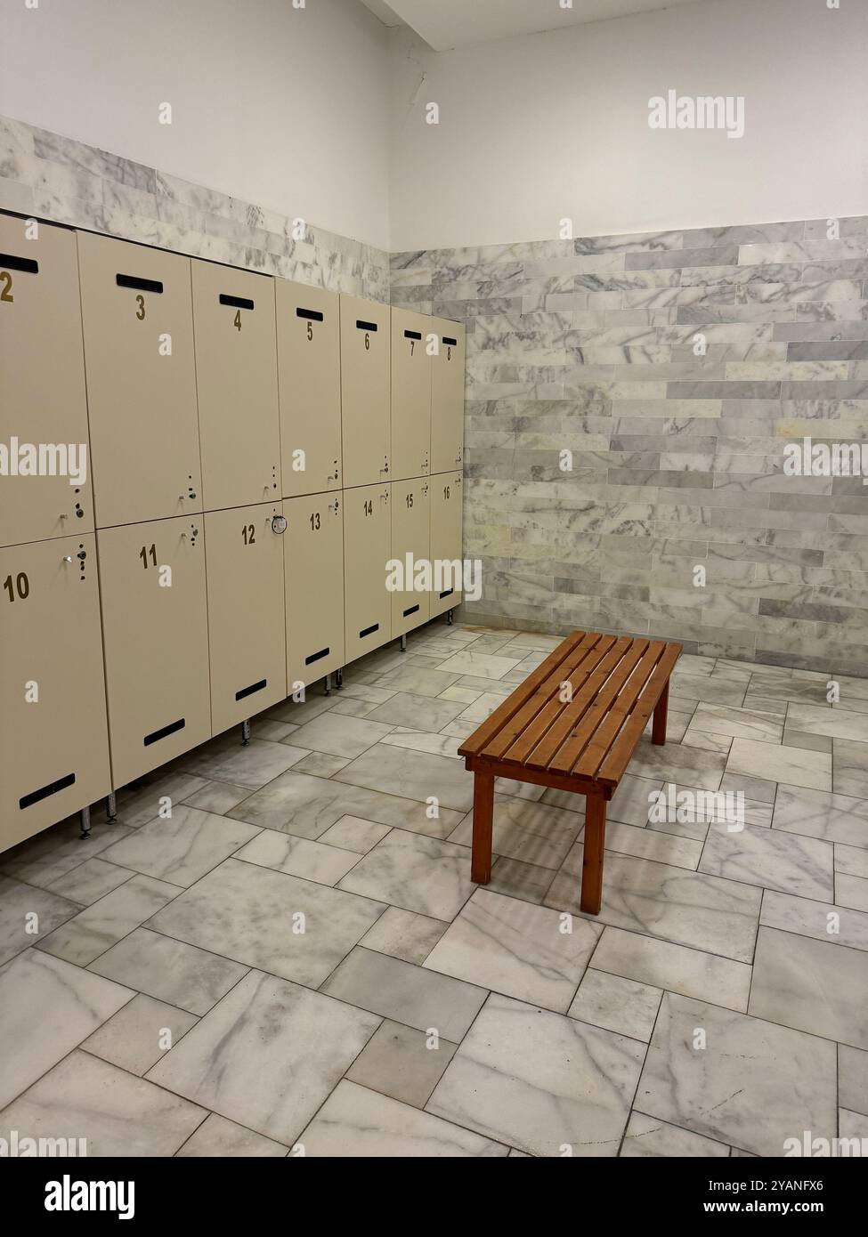 A styled locker room with wooden lockers, locks, and a bench to sit on ...