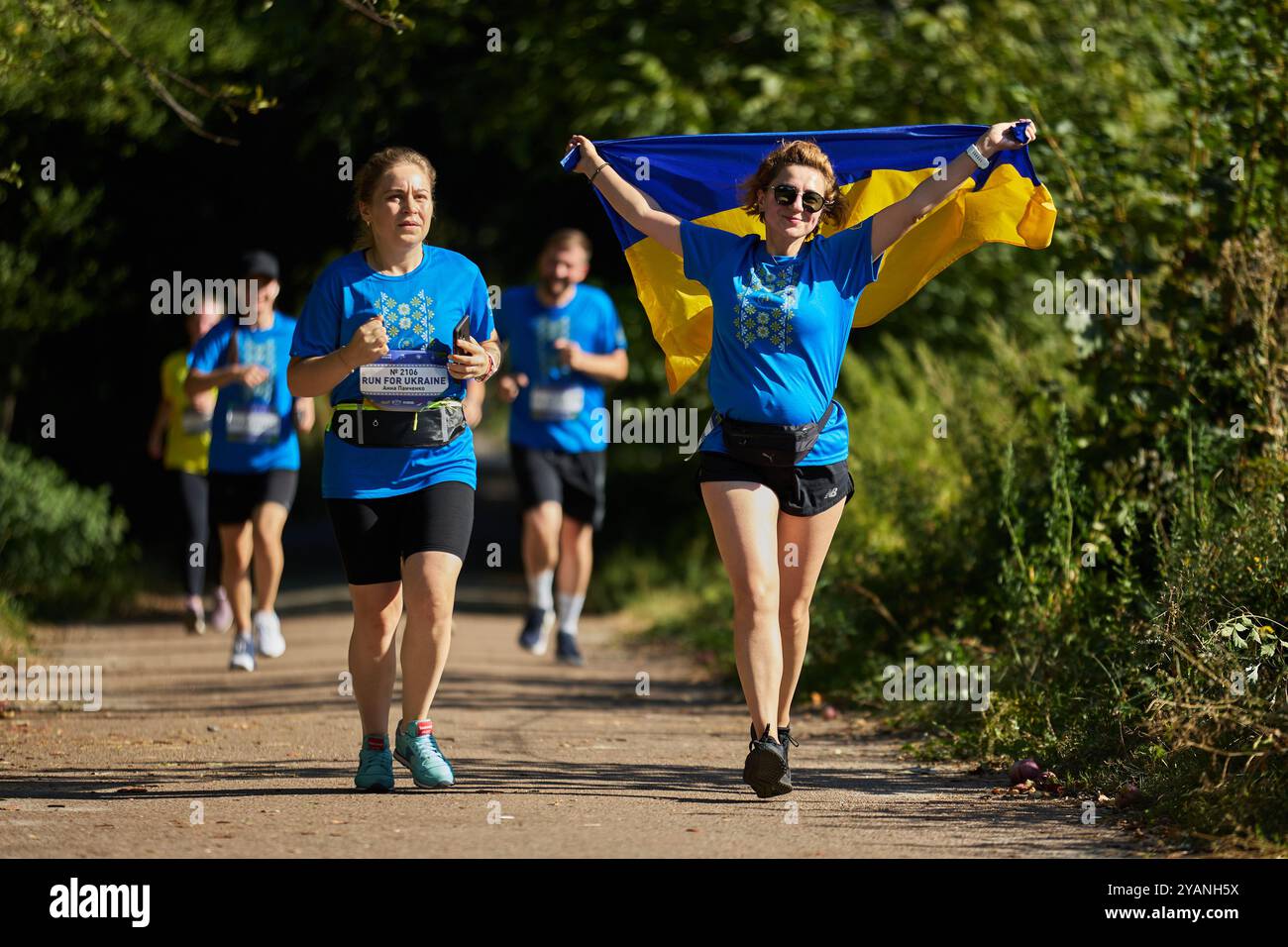 Cheerful Ukrainian woman runs with a national flag during marathon run ...