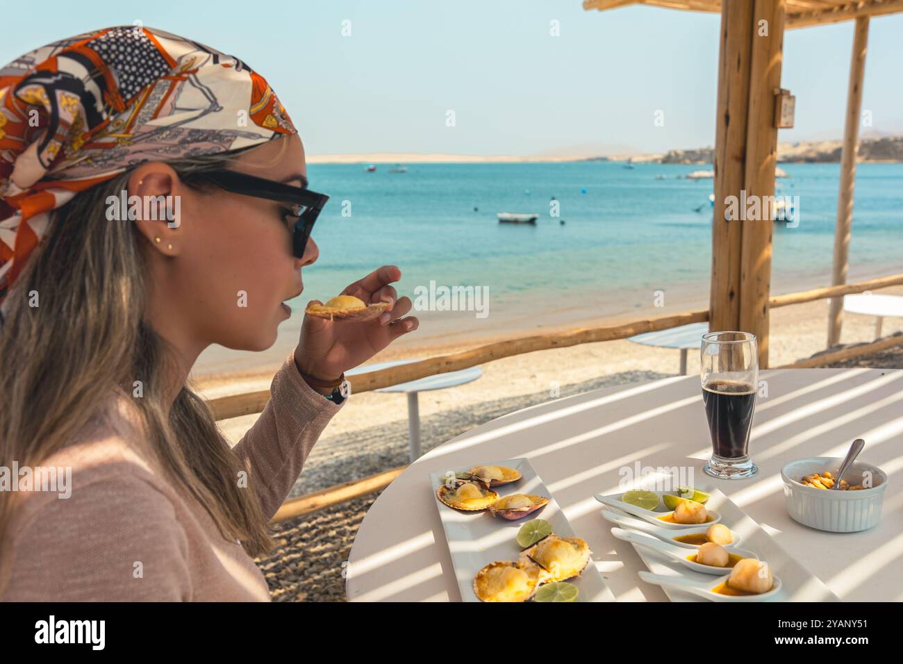 A woman is eating food at a beach Stock Photo - Alamy