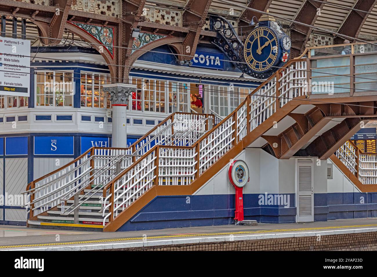 A railway station staircase leads up to a footbridge and an ornate ...