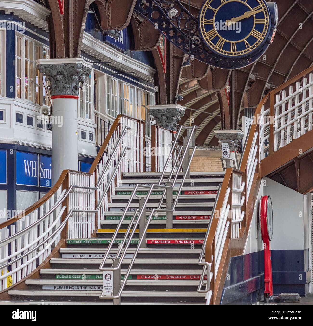 A railway station staircase leads up to a footbridge and an ornate ...