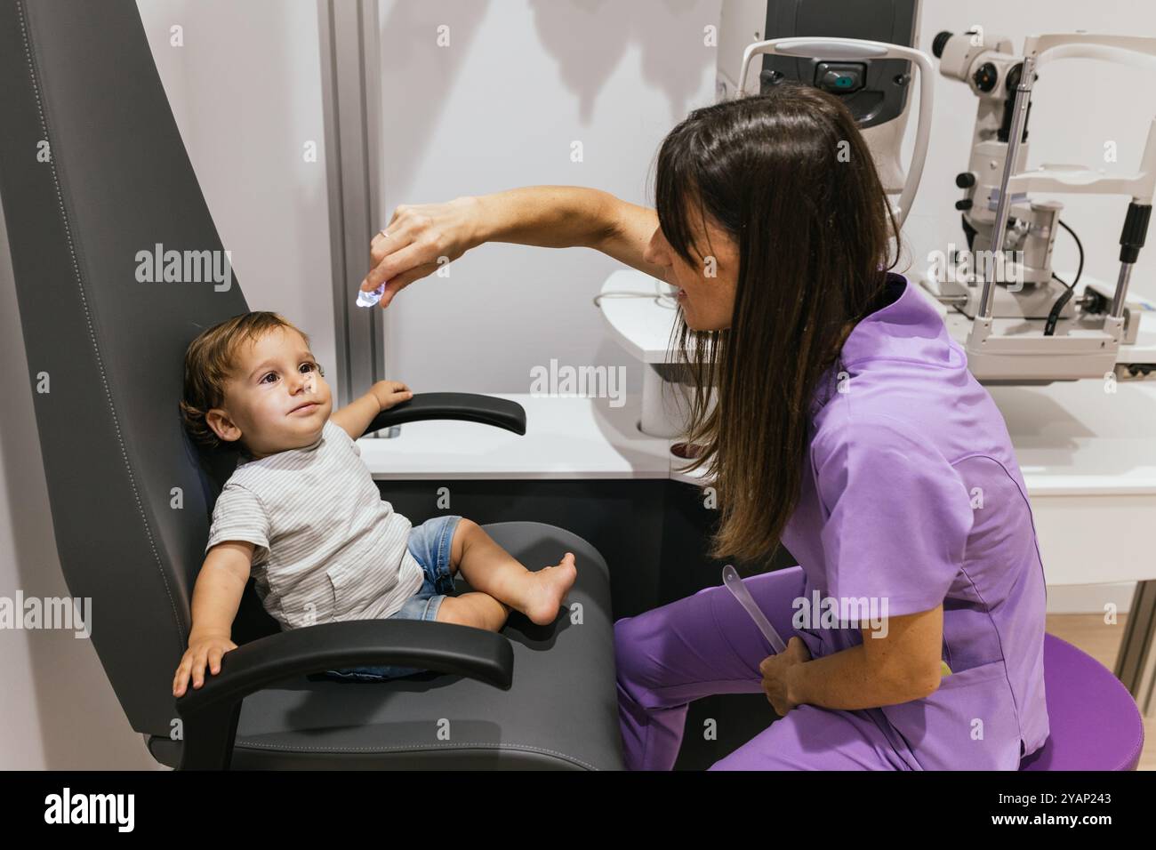 Optometrist performing eye examination on baby boy using flash cards ...