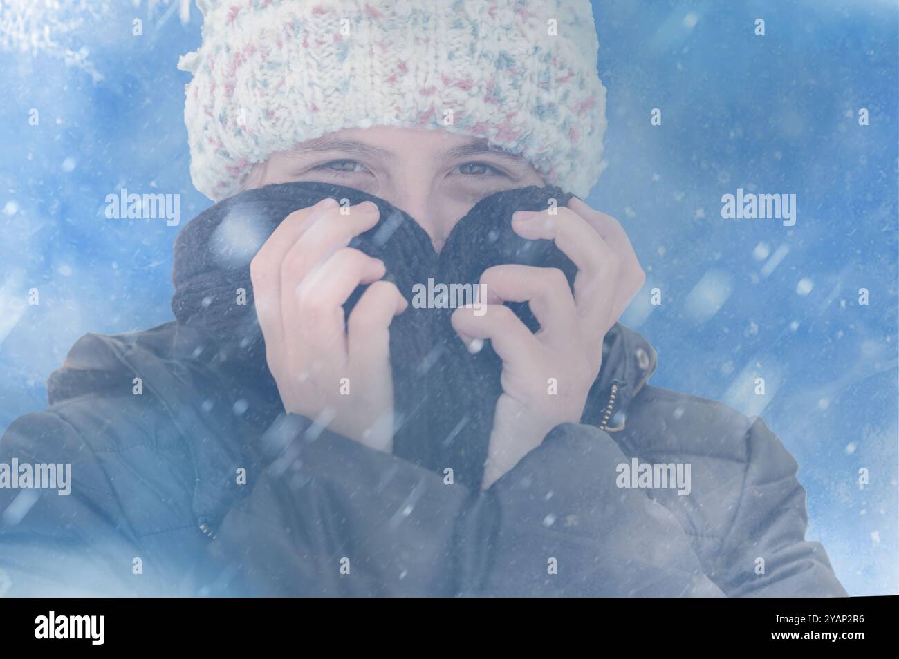 Frozen girl shivering from cold on blue snowy background. Girl during ...