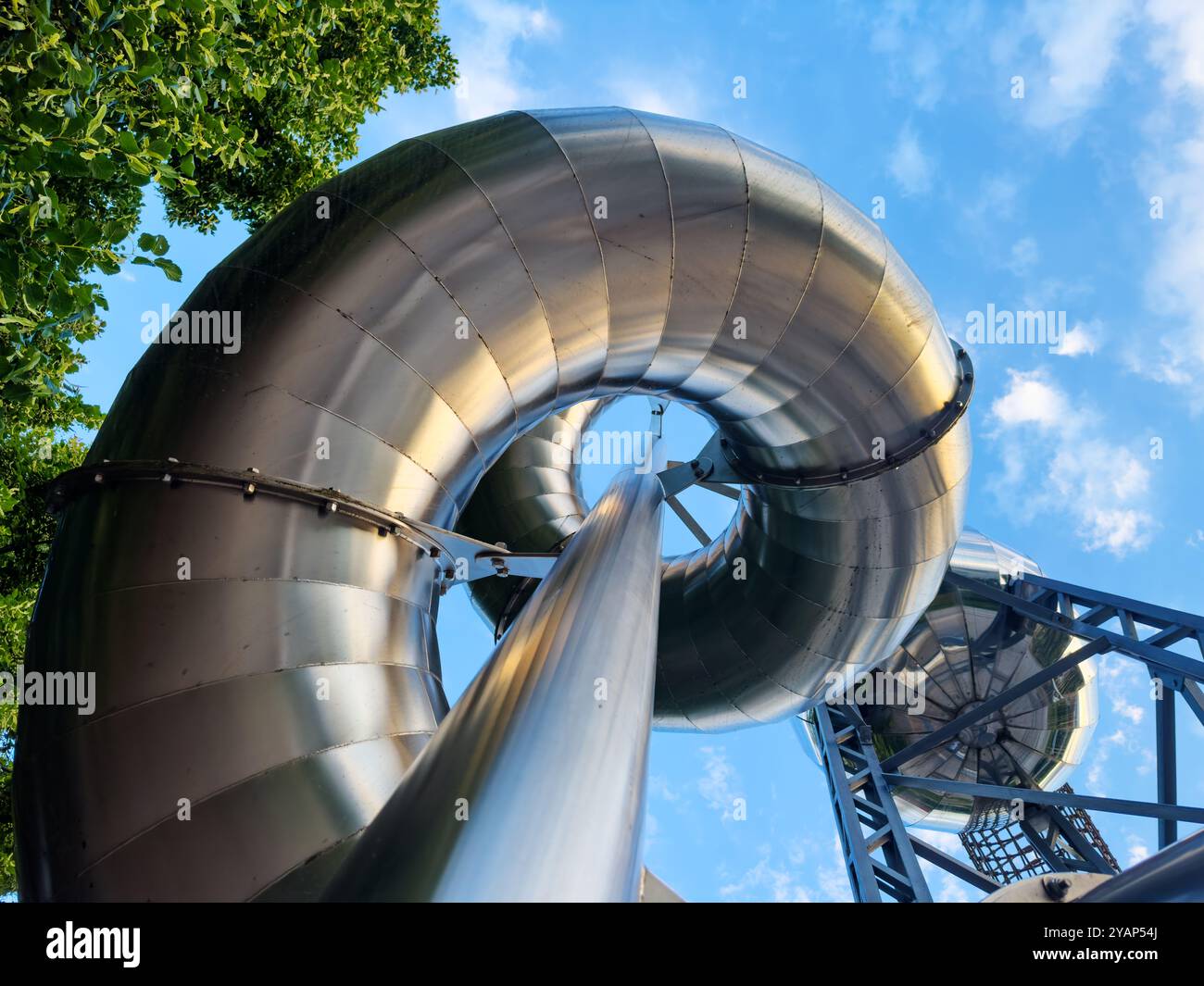 Curved metal slide structure leading up to the blue sky and tree Stock ...
