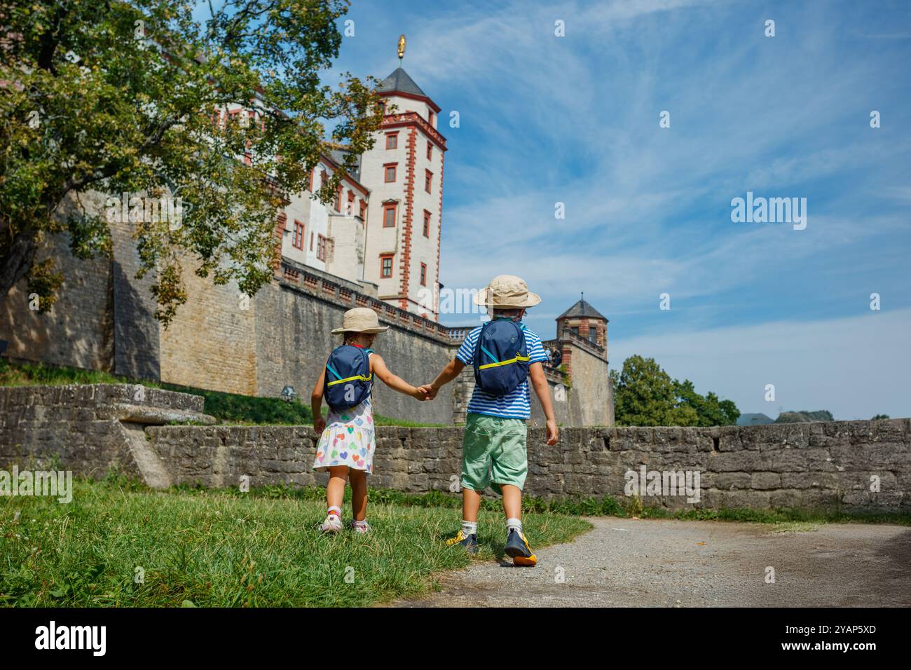 Holding hands, two kids walk along a path in Marienberg Fortress Stock ...