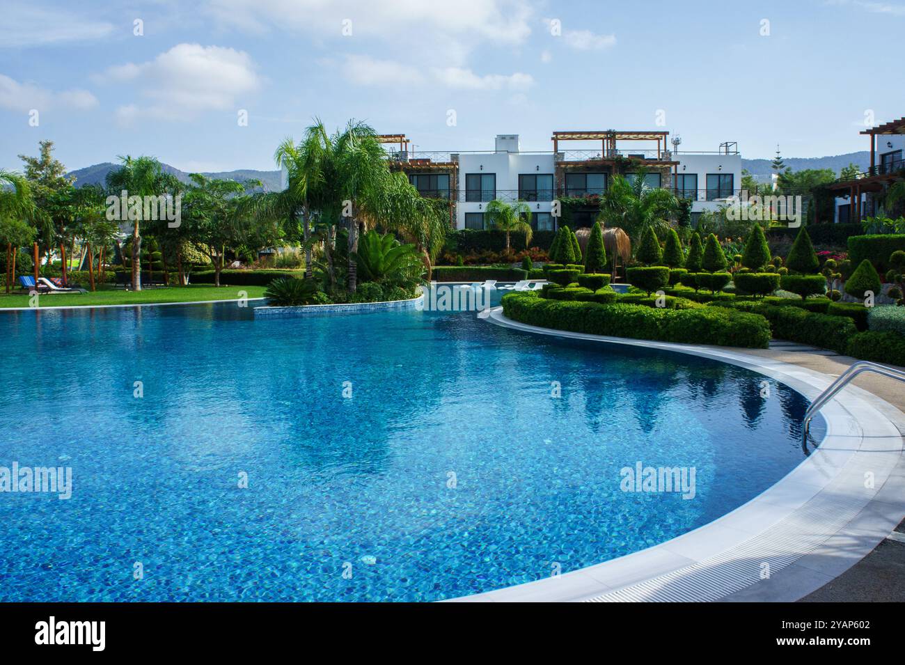 A serene setting unfolds with a sparkling blue pool reflecting the ...
