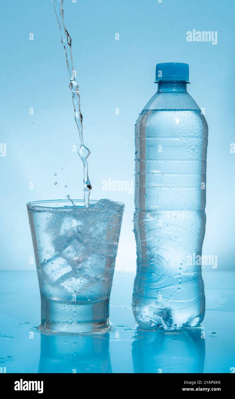 Water stream splashing on frozen glass cup filled with water and ice ...