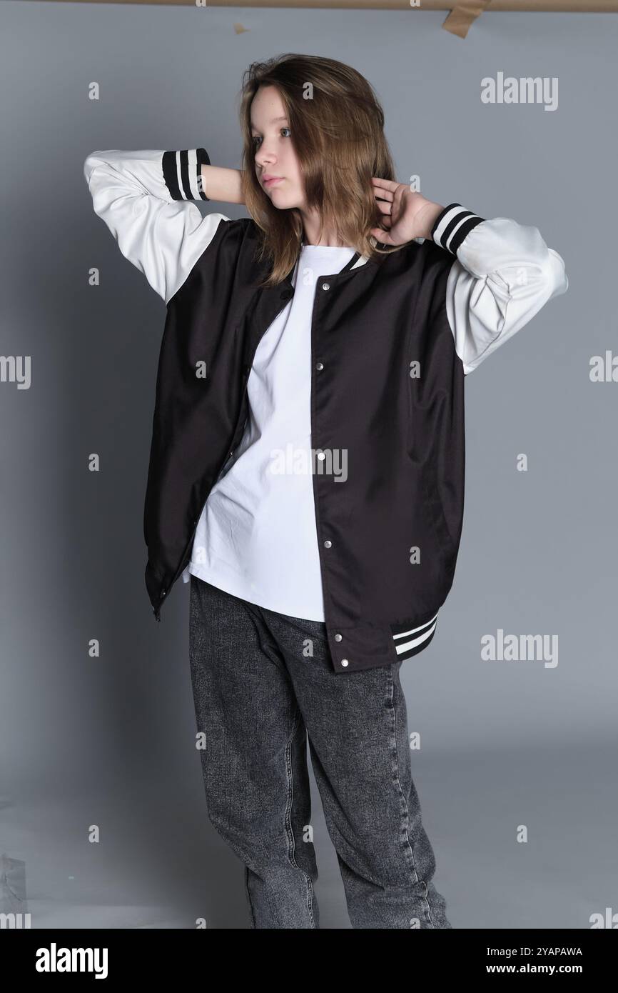 Side view of a teenage girl casually draping a varsity jacket over her ...
