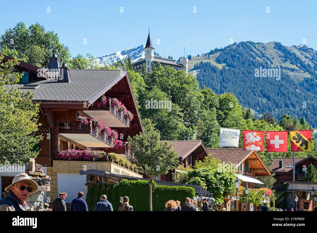 street scene, Swiss style buildings, people, colorful flags, flowers, Gstaad Palace Hotel ...