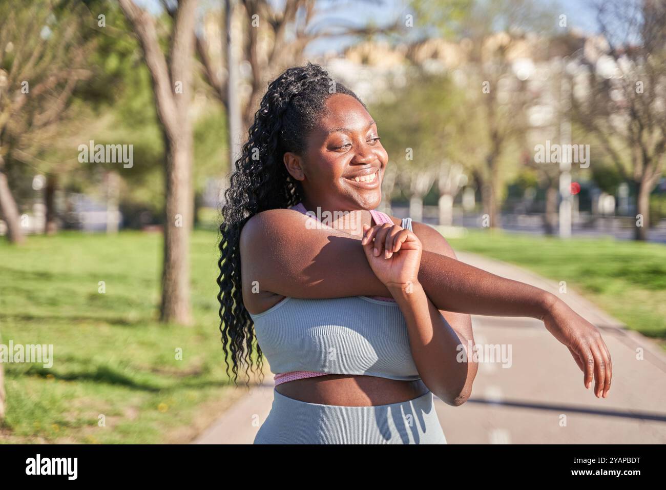 Attractive young woman warming up, stretching her arms before morning ...