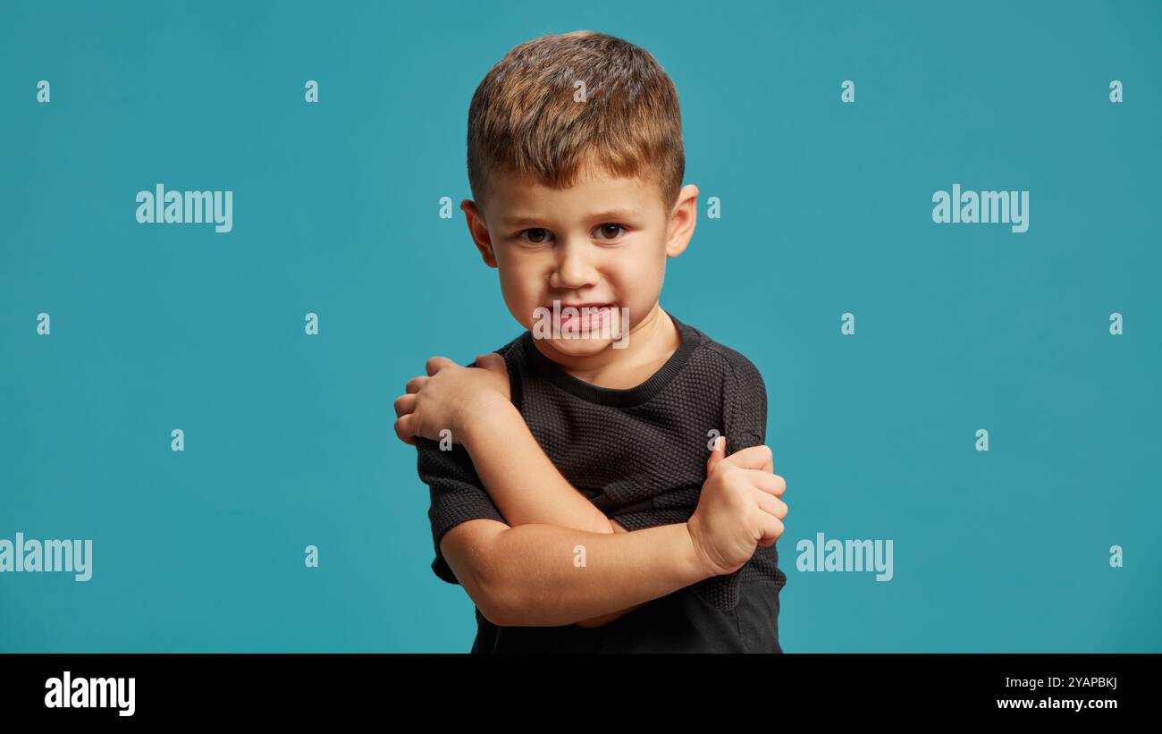 Boy shows hint of frustration, his arms crossed as he shows determined ...