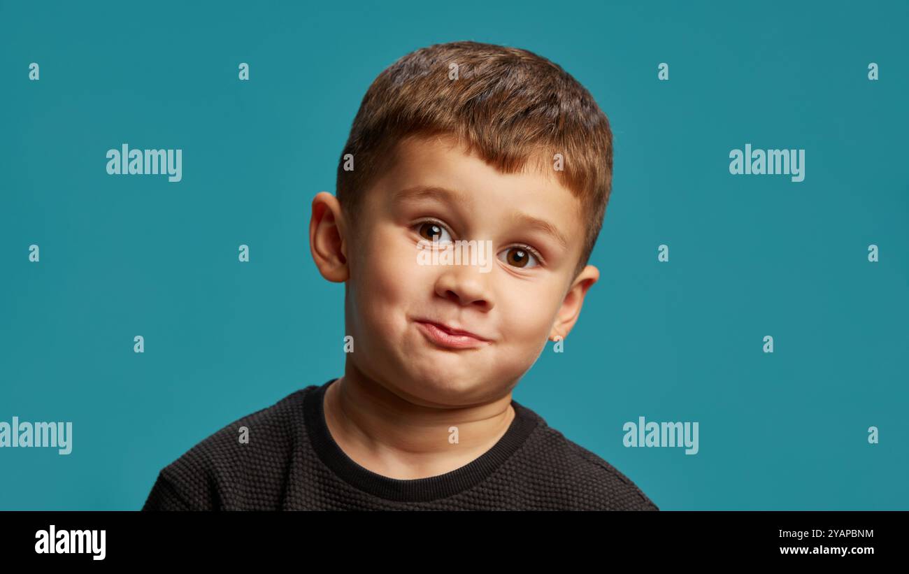 Little boy pulls playful face, smirk with his lips puckered, giving ...