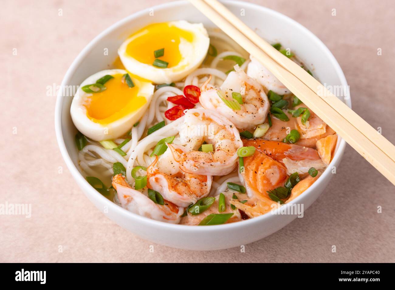 Asian dish with broth, noodles, tiger shrimp, fish, egg and green ...