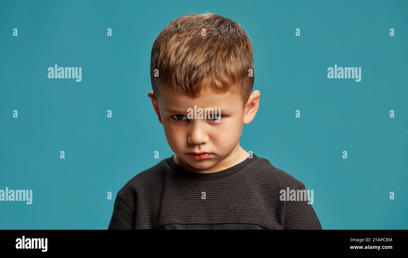 Little boy stares intently with a serious, determined expression ...