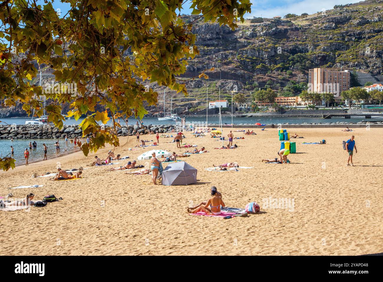Holidaymakers and people sunbathing on vacation on the man made beach ...