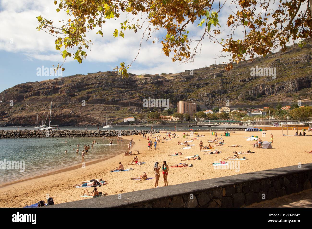 Holidaymakers and people sunbathing on vacation on the man made beach ...