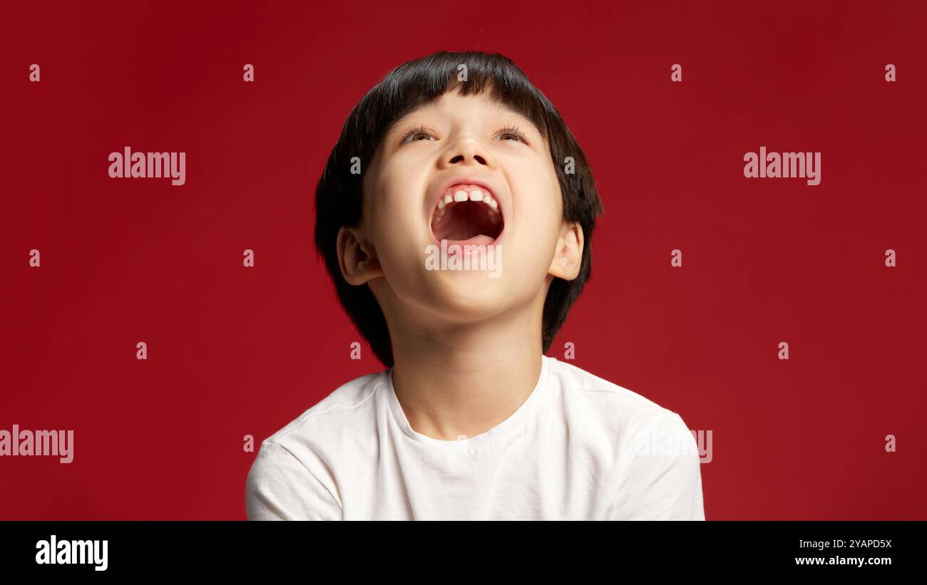Child, Asian boy laughs with his head thrown back, mouth wide open ...