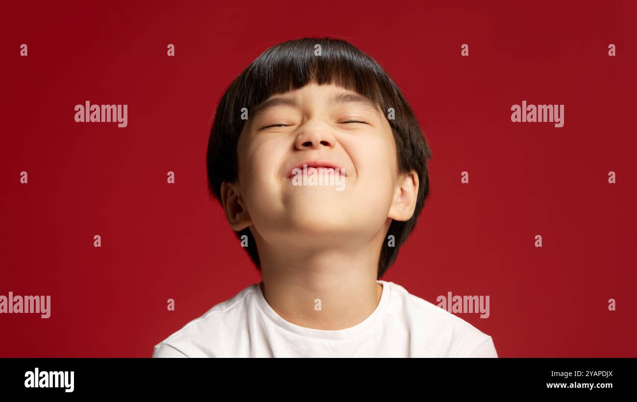 Little boy with closed eyes and wide grin, expressing pure joy against ...