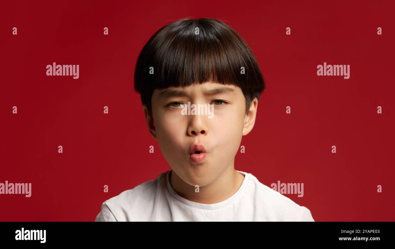 Little boy, child slightly frowning and pouting, lips pursed as if ...