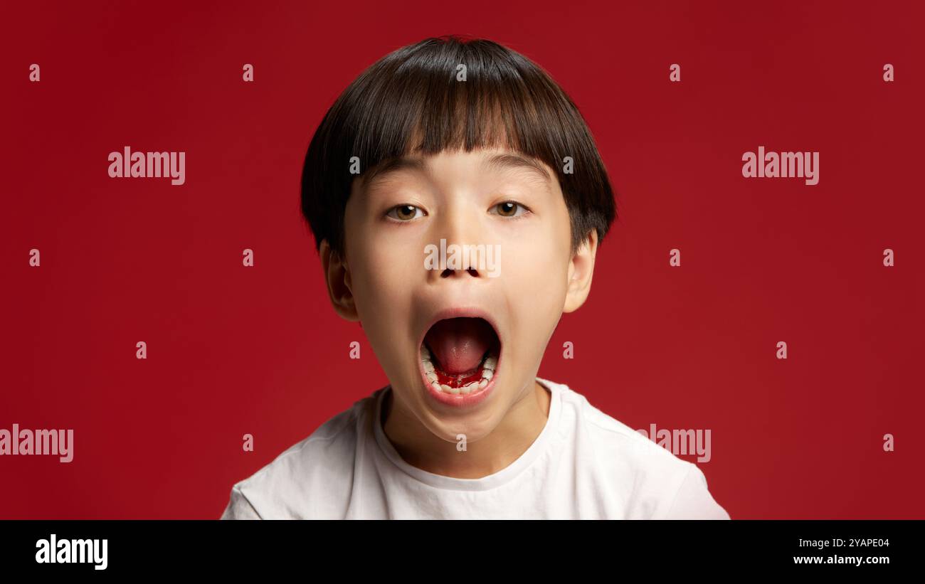 Little Asian oy, child playfully yawning or shouting with mouth wide ...