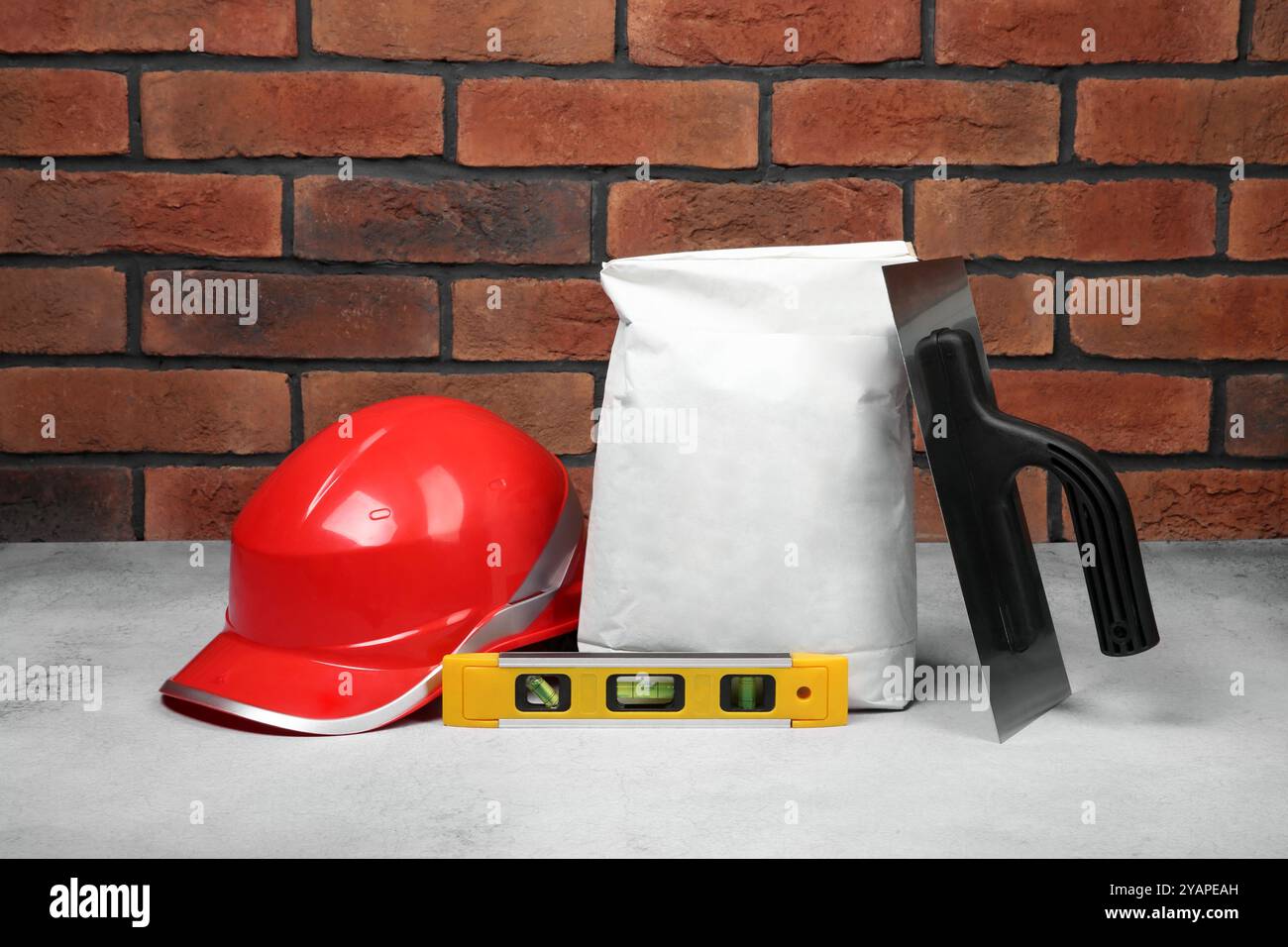 Bag of cement and construction tools on light textured table against ...