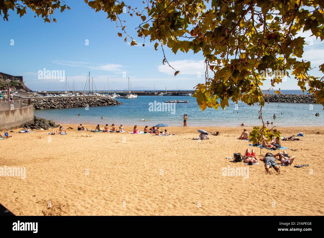 Holidaymakers and people sunbathing on vacation on the man made beach ...