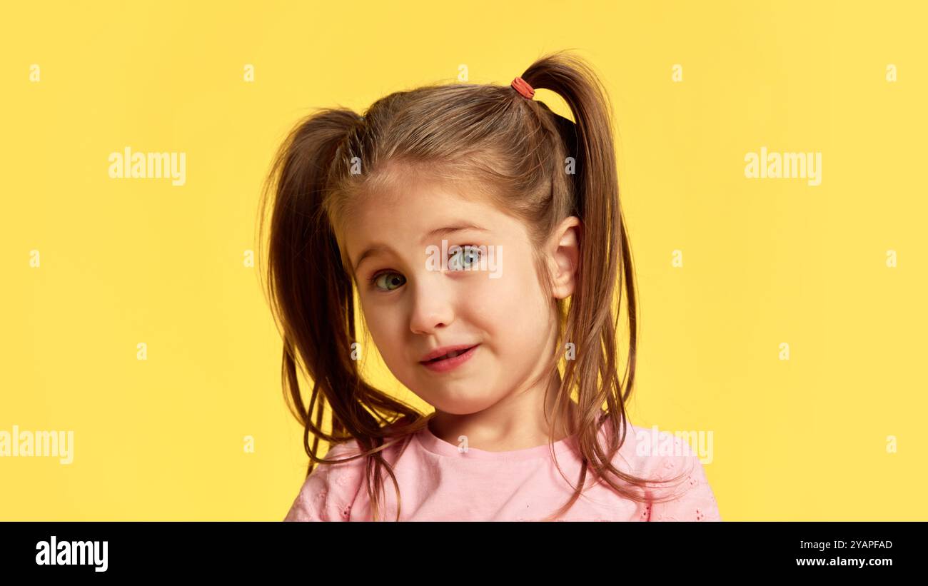 With slightly tilted head and amused expression, girl gives curious ...