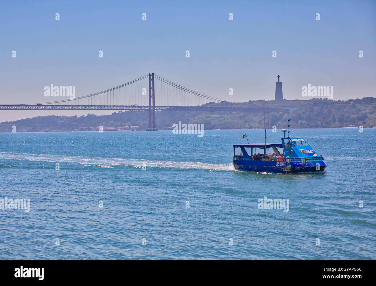 Tourist boat on the river Tagus Tejo river with Cristo Rei statue and ...