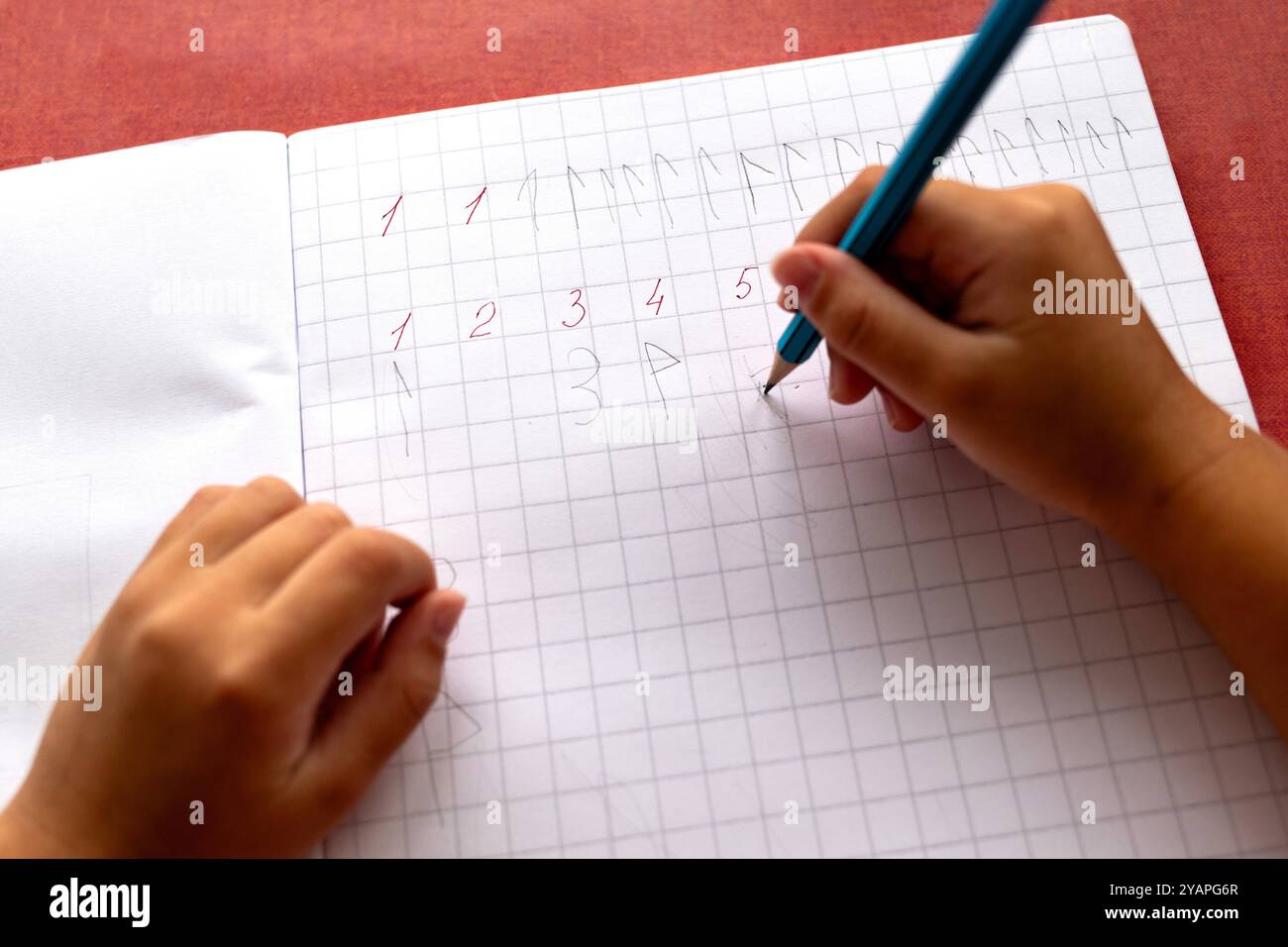 Child's hands writing numbers in a notebook. The problem of dysgraphia ...