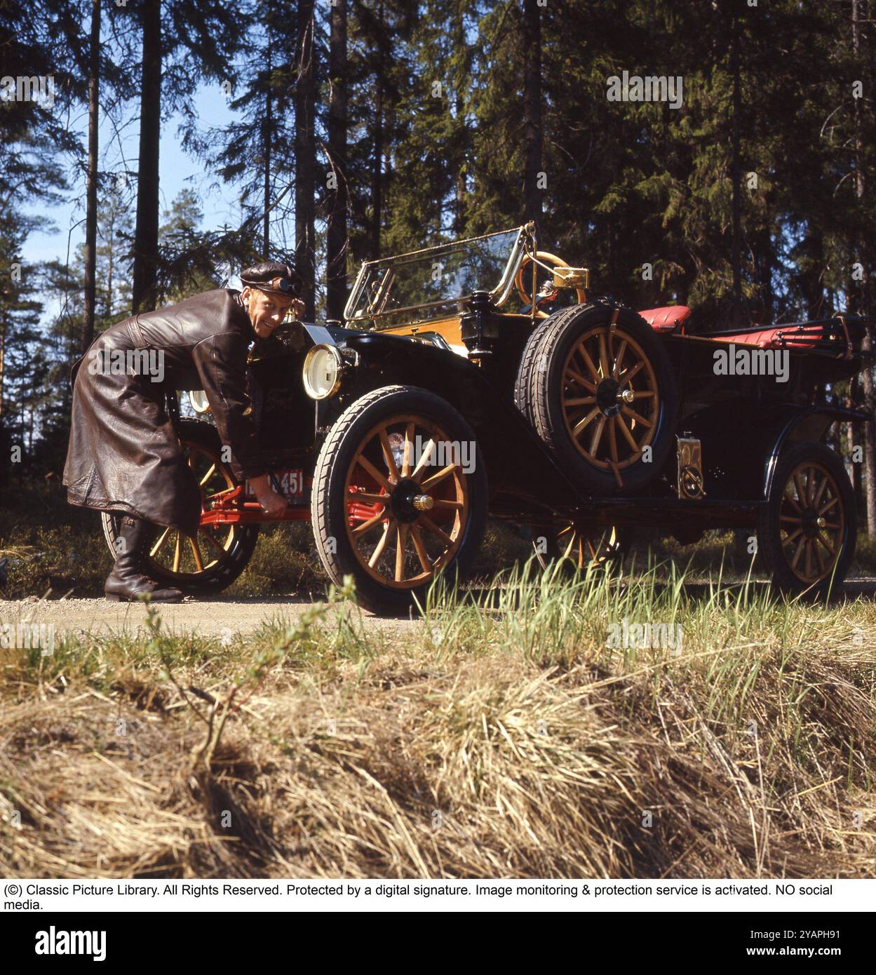 The old car. A man in a typical old fashioned driver's outfit complete ...