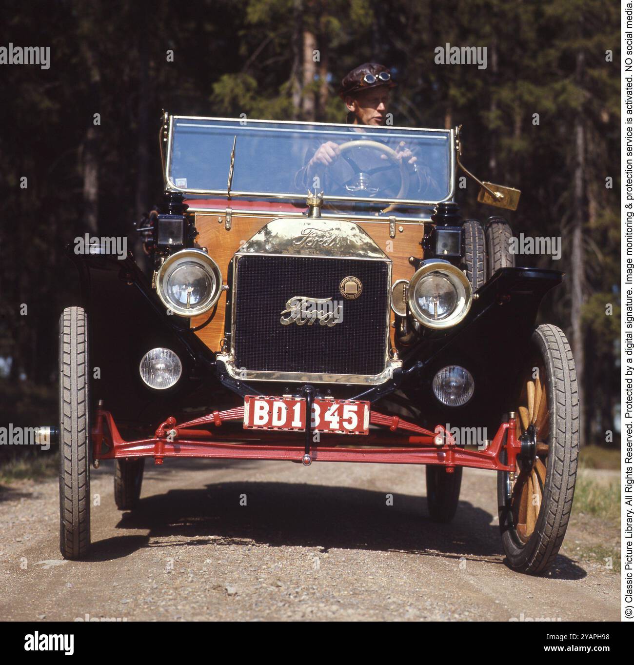 The old car. A man in a typical old fashioned driver's outfit complete ...